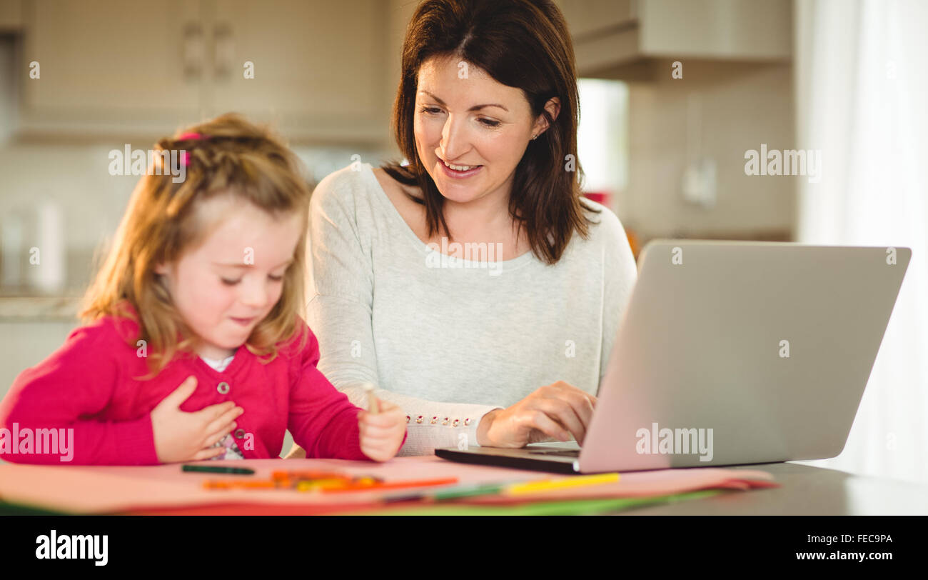 Mother on laptop while daughter drawing Stock Photo - Alamy