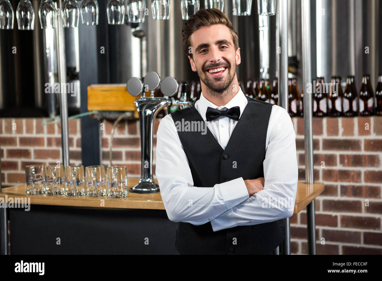 Handsome barman smiling at camera with arms crossed Stock Photo - Alamy