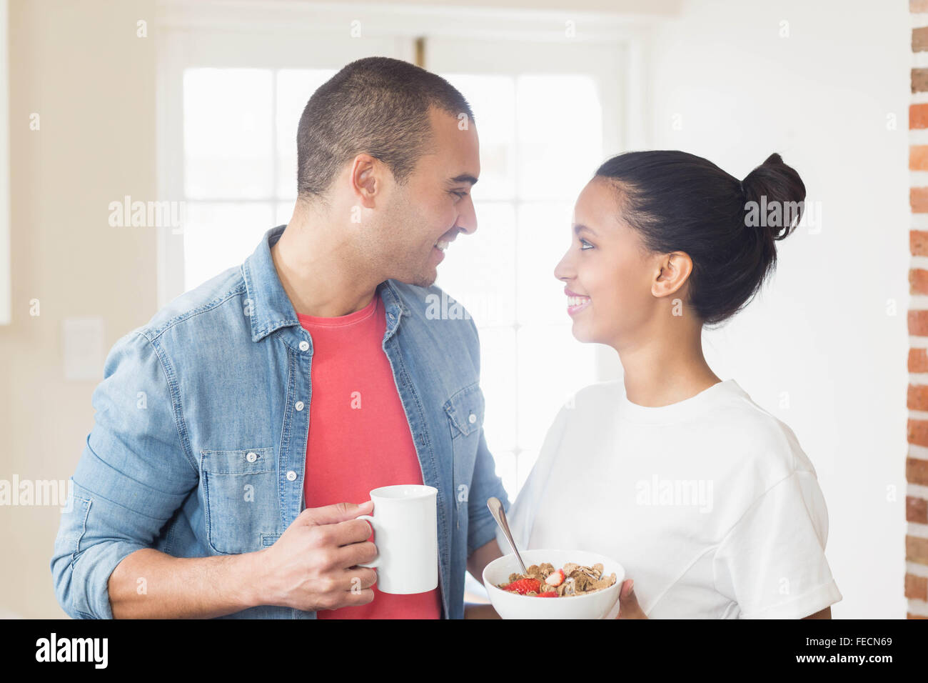 Smiling couple eating breakfast together in the kitchen Stock Photo - Alamy