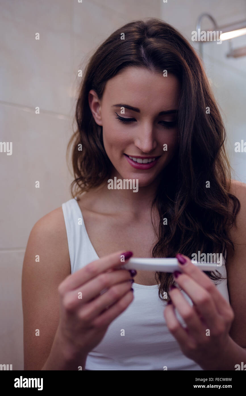 Happy beautiful brunette looking at a pregnancy test Stock Photo - Alamy