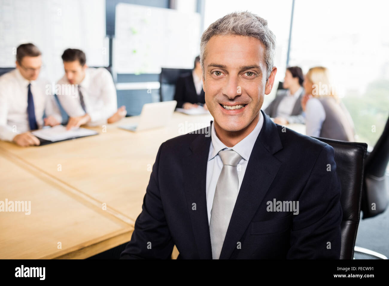 Businessman smiling at the camera during meeting Stock Photo - Alamy