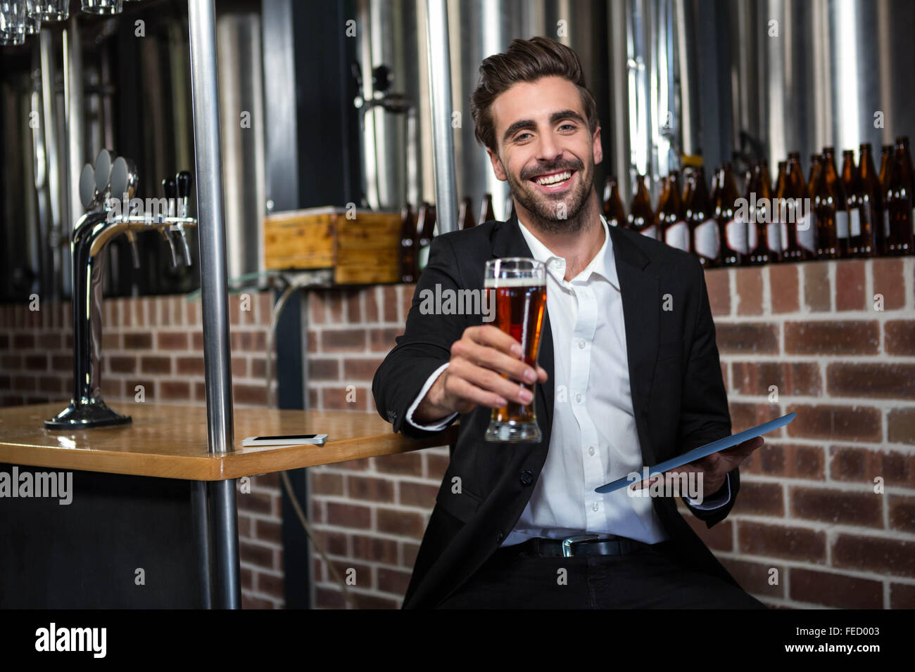 Handsome man holding beer and tablet Stock Photo - Alamy