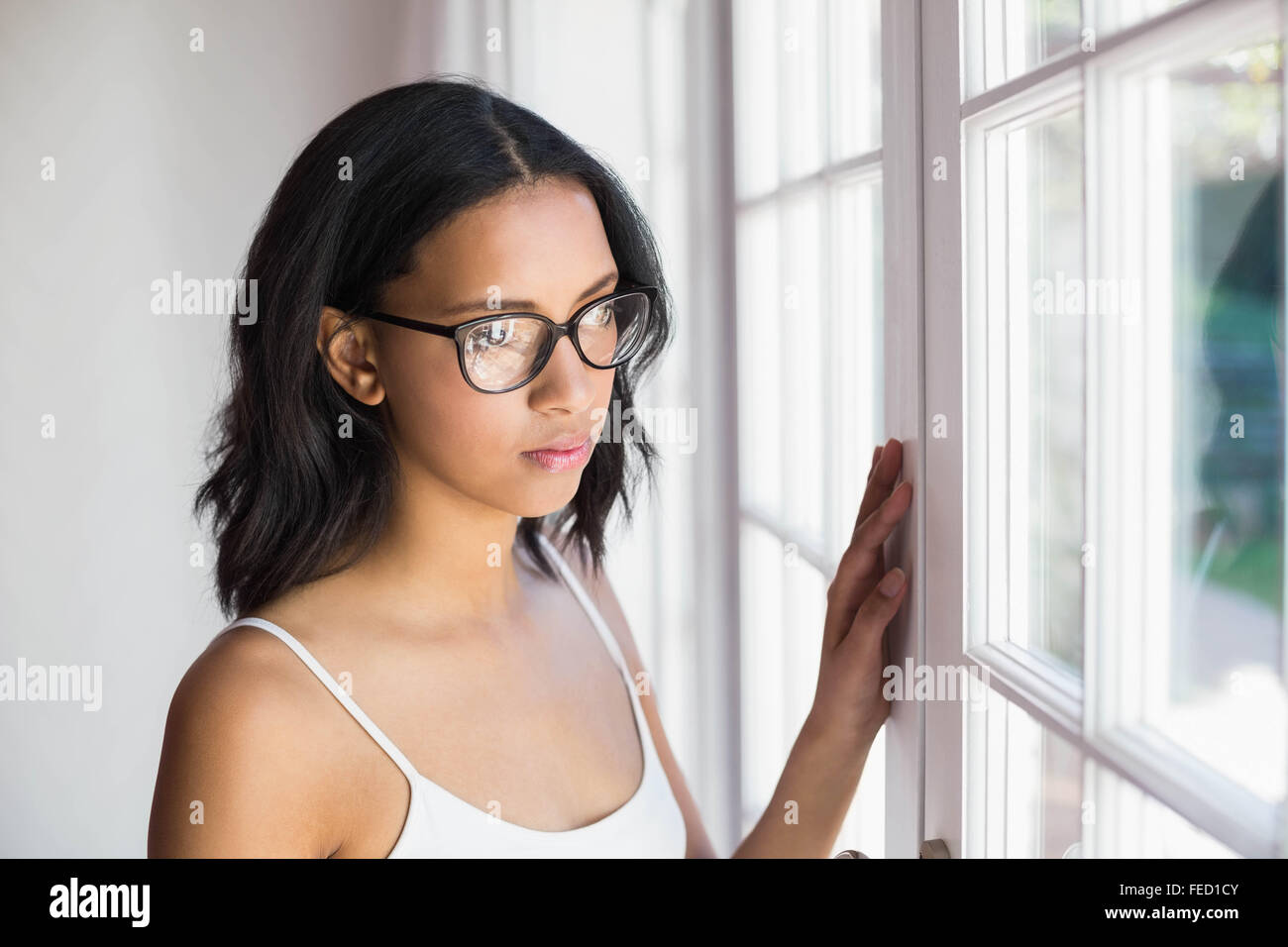 Thoughtful brunette looking through window Stock Photo - Alamy