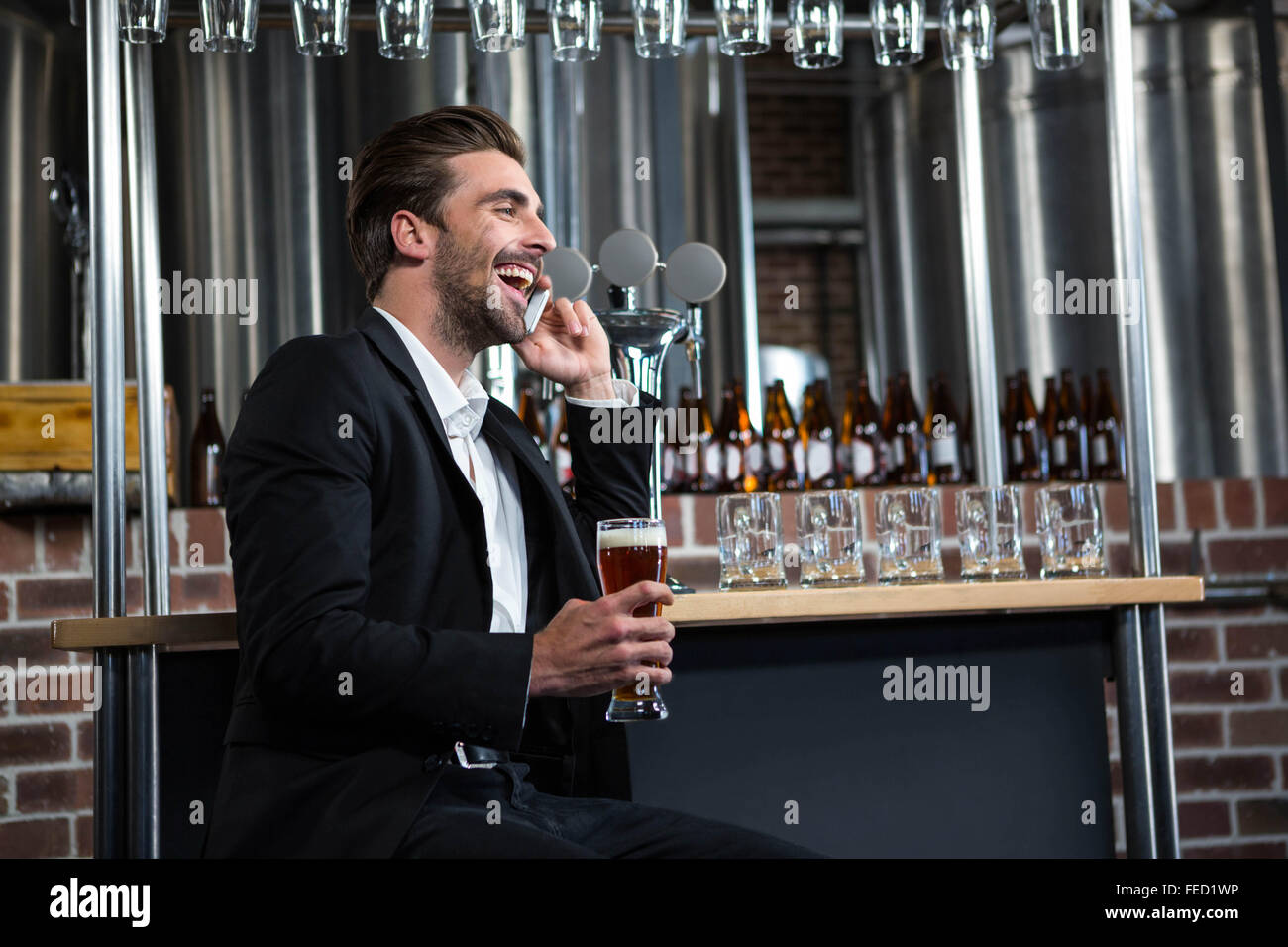 Handsome businessman holding a pint and calling Stock Photo - Alamy