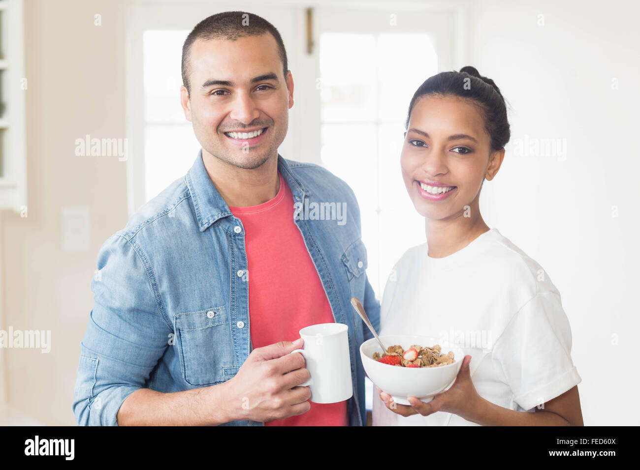 Smiling couple eating breakfast together in the kitchen Stock Photo - Alamy