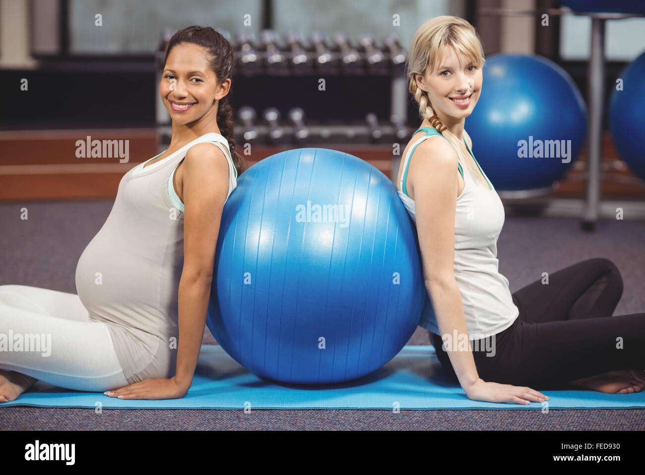Smiling women leaning back on fitness ball Stock Photo - Alamy