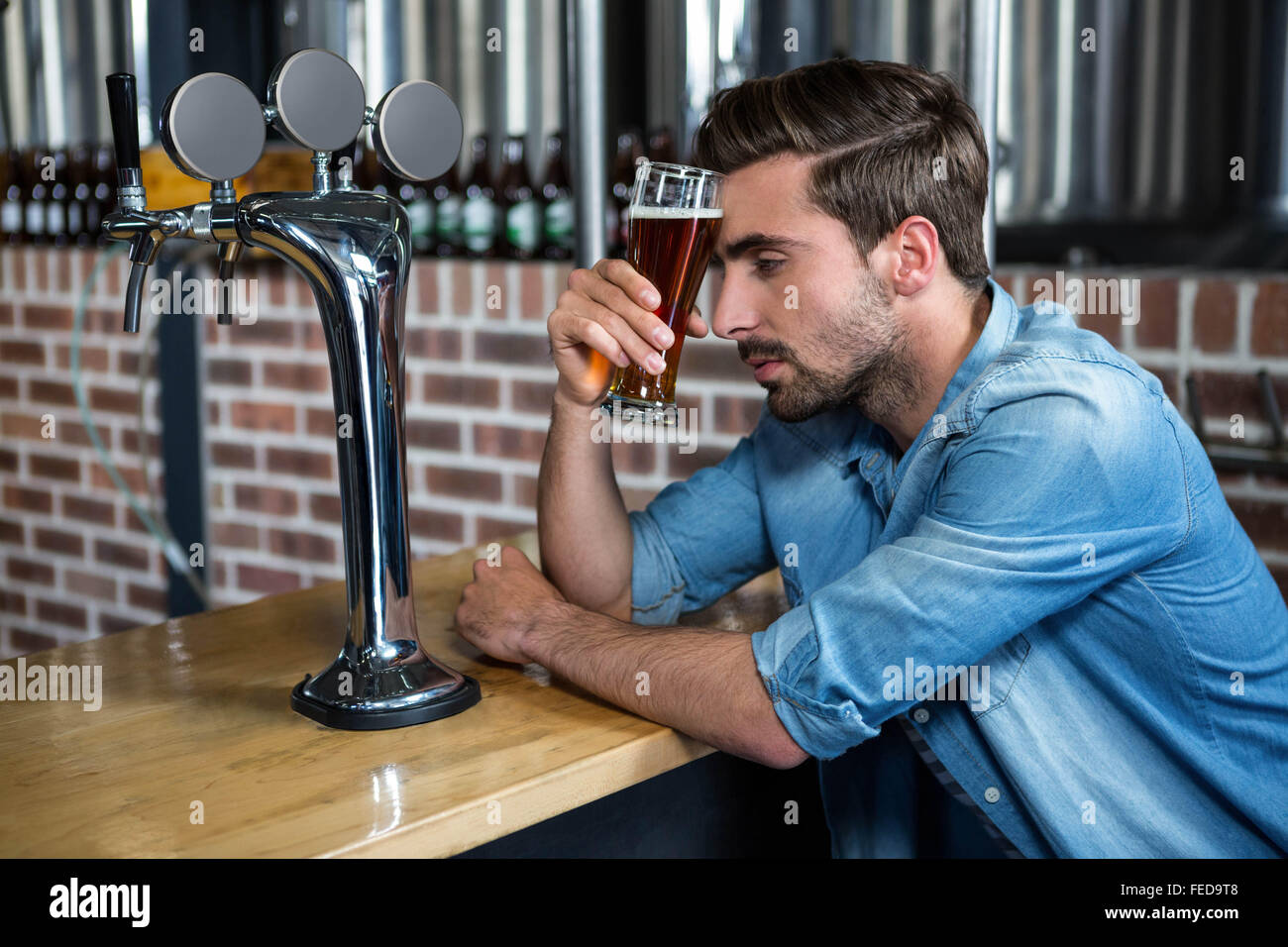 Tired man leaning on counter Stock Photo - Alamy