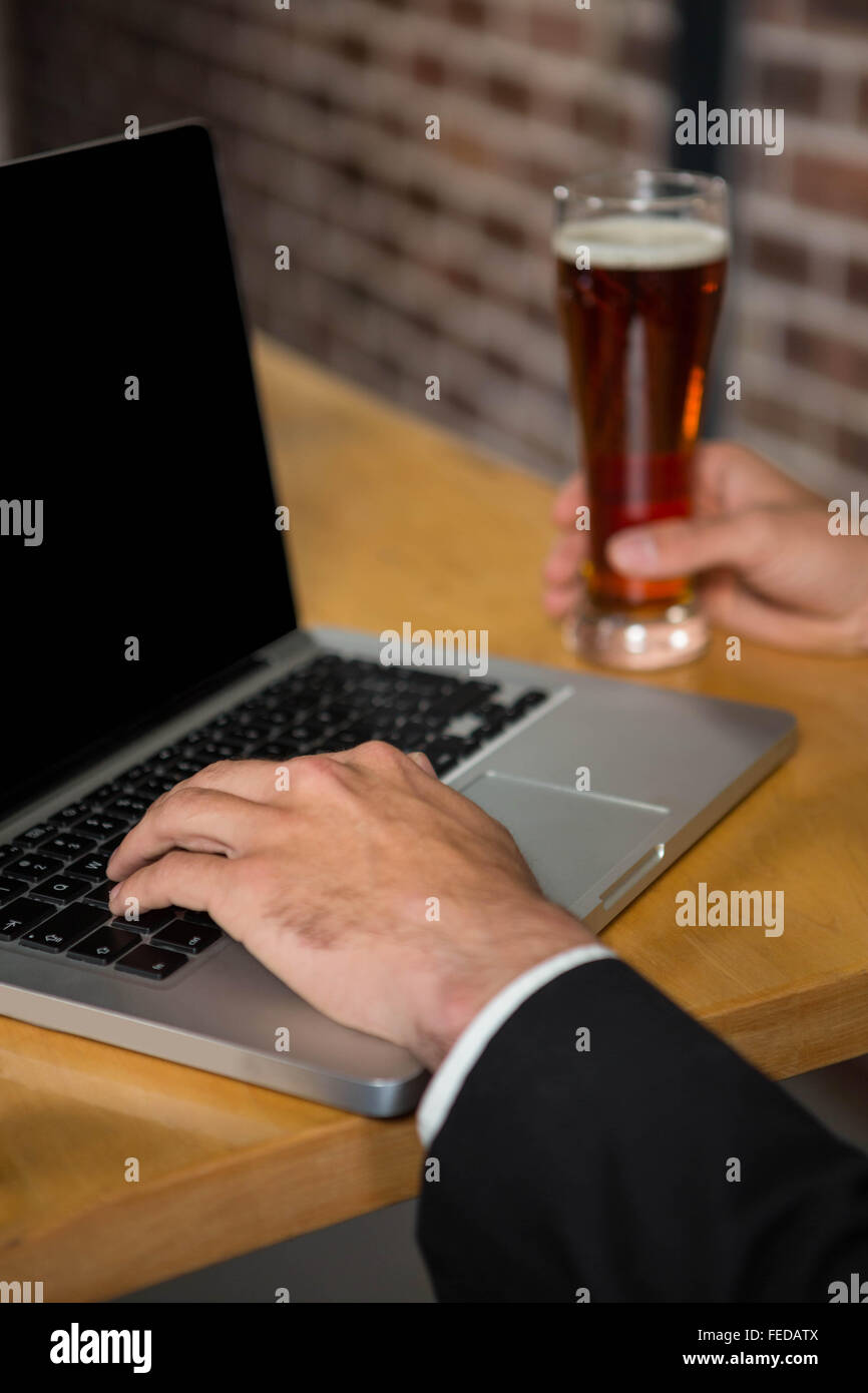 Businessman having a drink while working on his laptop Stock Photo - Alamy