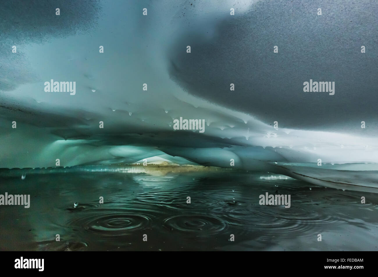 Ice cave melting and dripping onto the surface of a tarn below Camp ...
