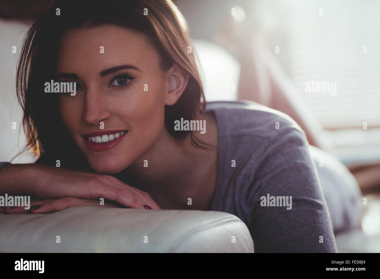 Beautiful brunette leaning on the couch Stock Photo - Alamy