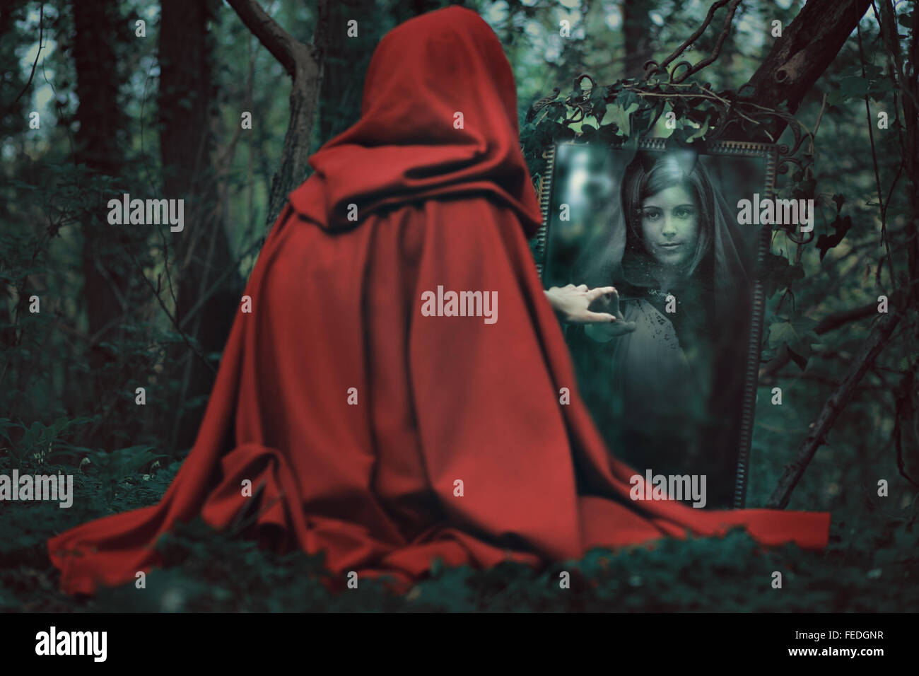 Mysterious red hooded woman in front of a magical mirror. Dark fantasy ...