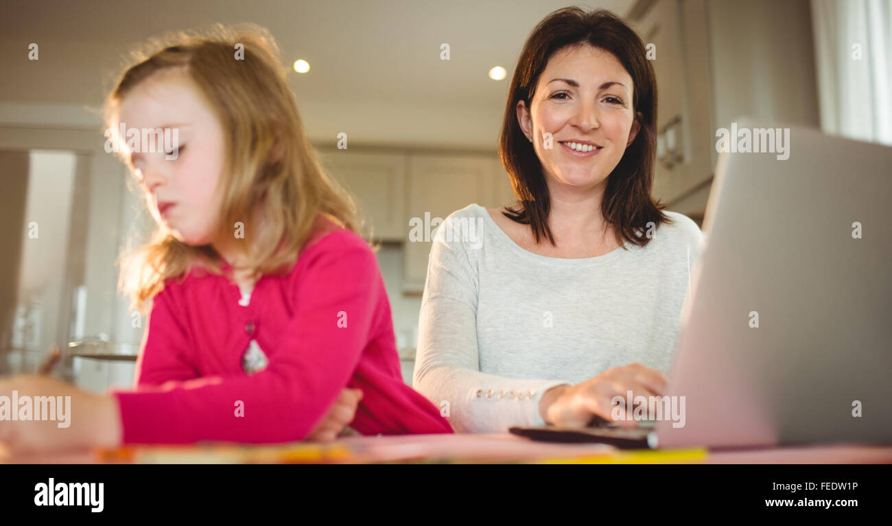 Mother on laptop while daughter drawing Stock Photo - Alamy