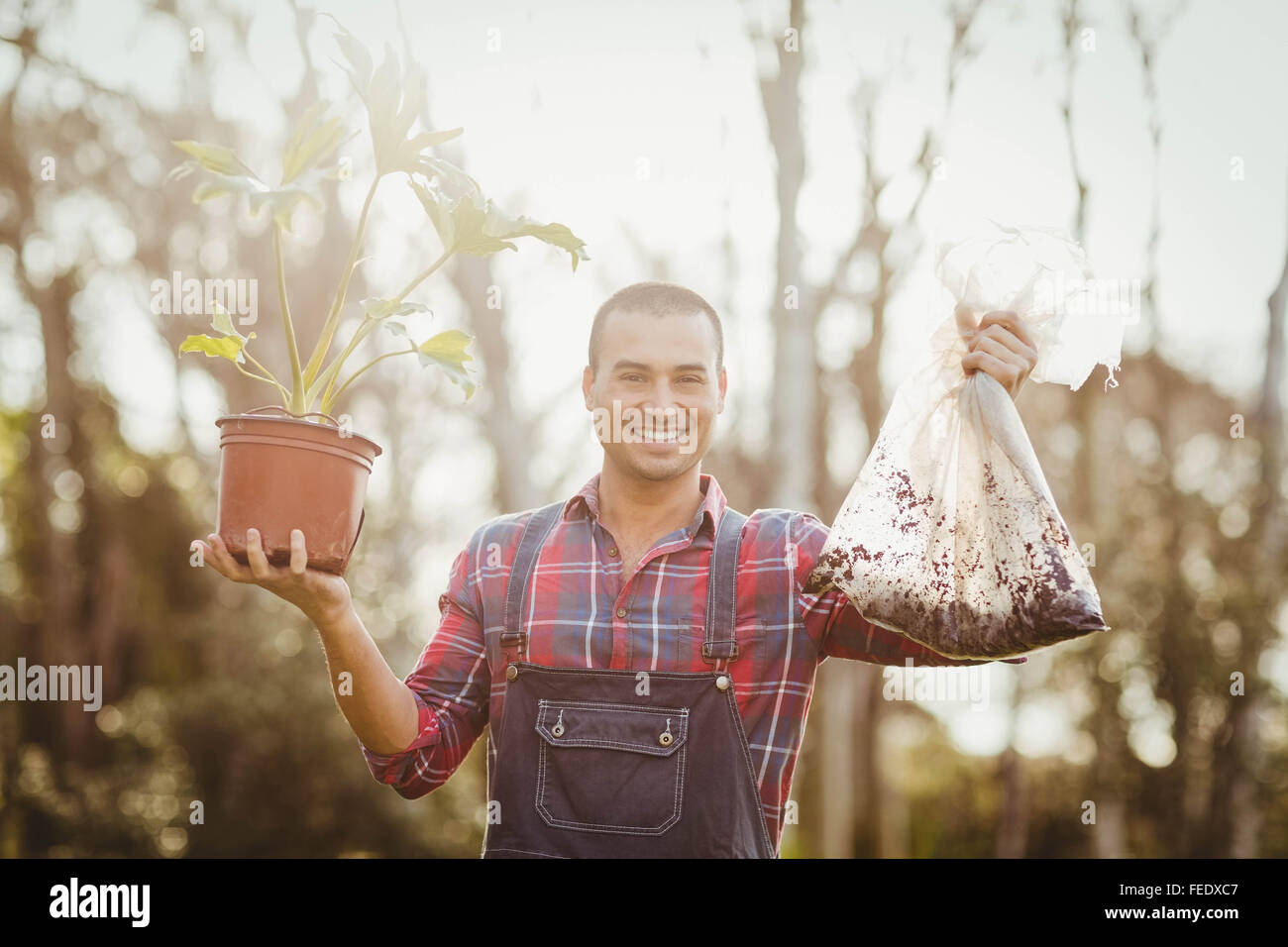 Smiling gardener showing a plant and a plastic bag Stock Photo - Alamy