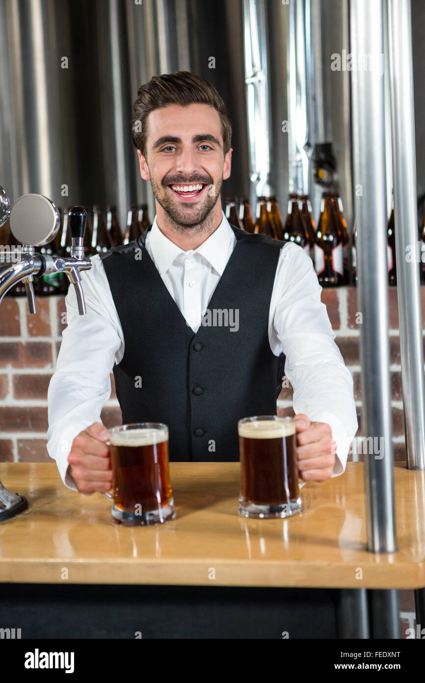 Handsome barman giving two beers Stock Photo - Alamy