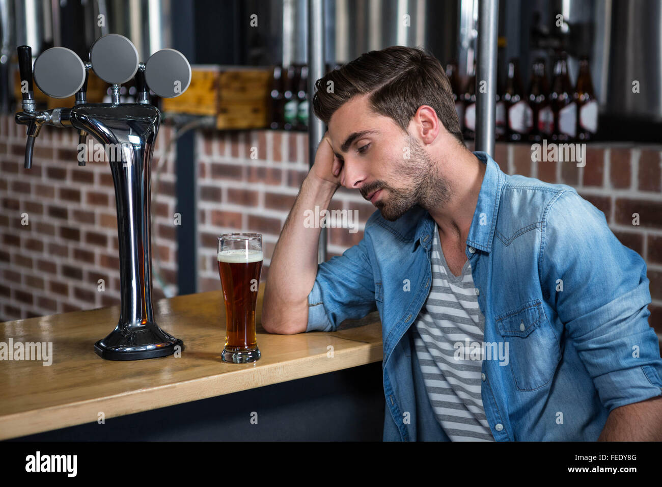 Tired man leaning on counter Stock Photo - Alamy
