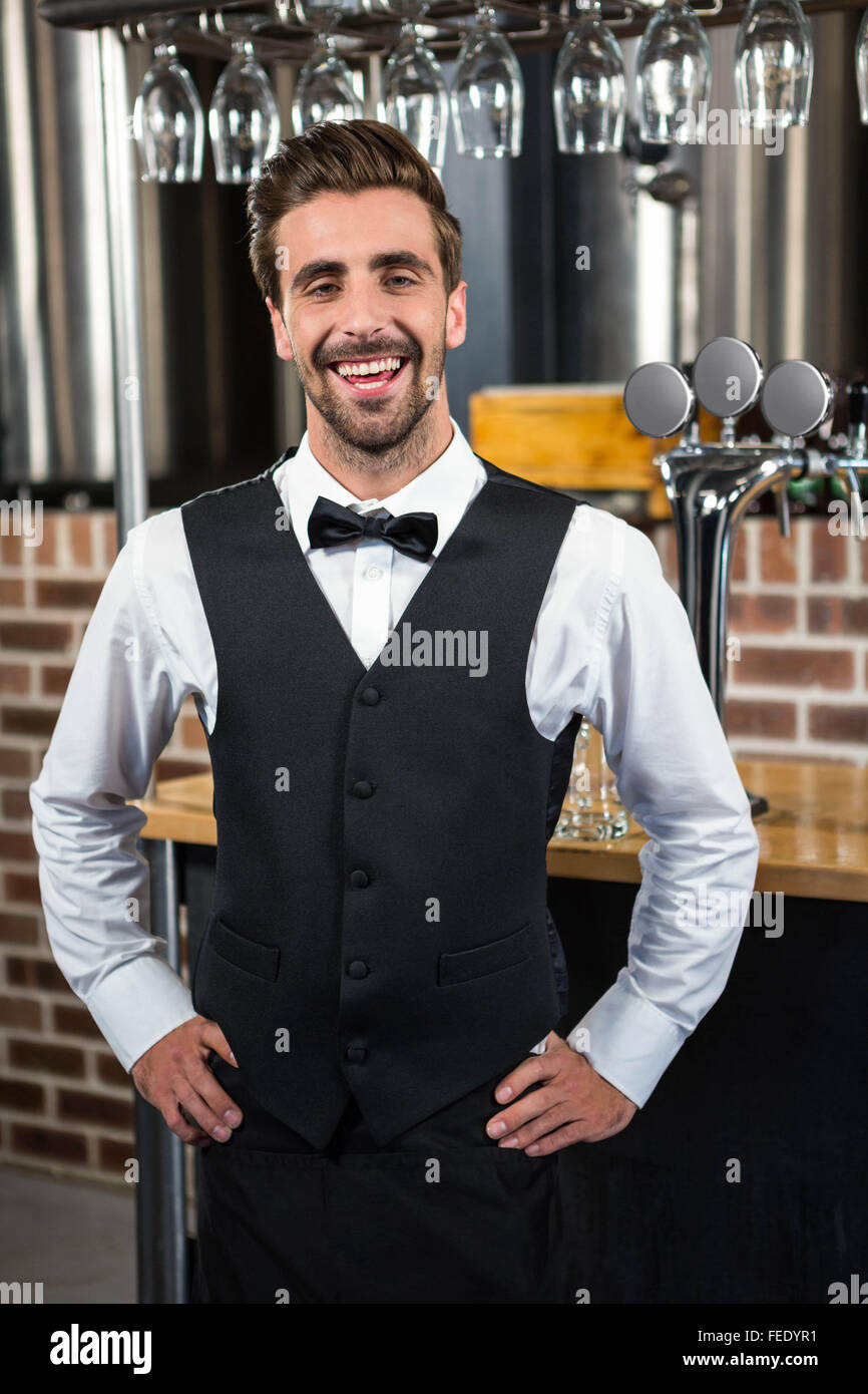 Handsome barman smiling at camera with hands on hips Stock Photo - Alamy