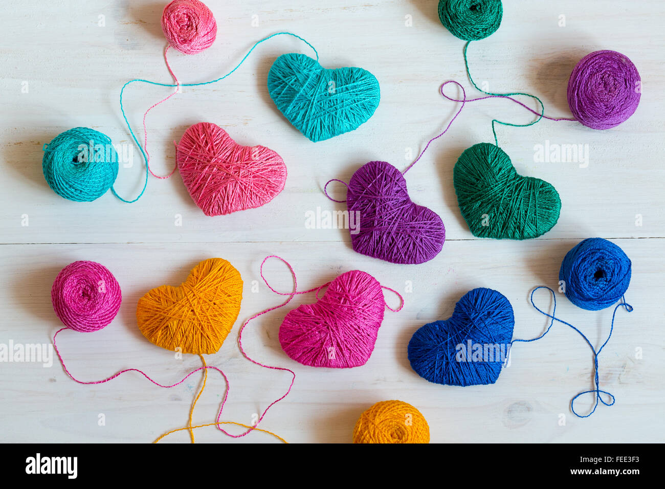 Multicolored Hearts with a balls of thread on white wooden background ...