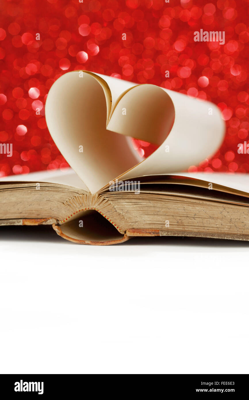 Pages of open book rolled in heart shape on glitter background Stock ...