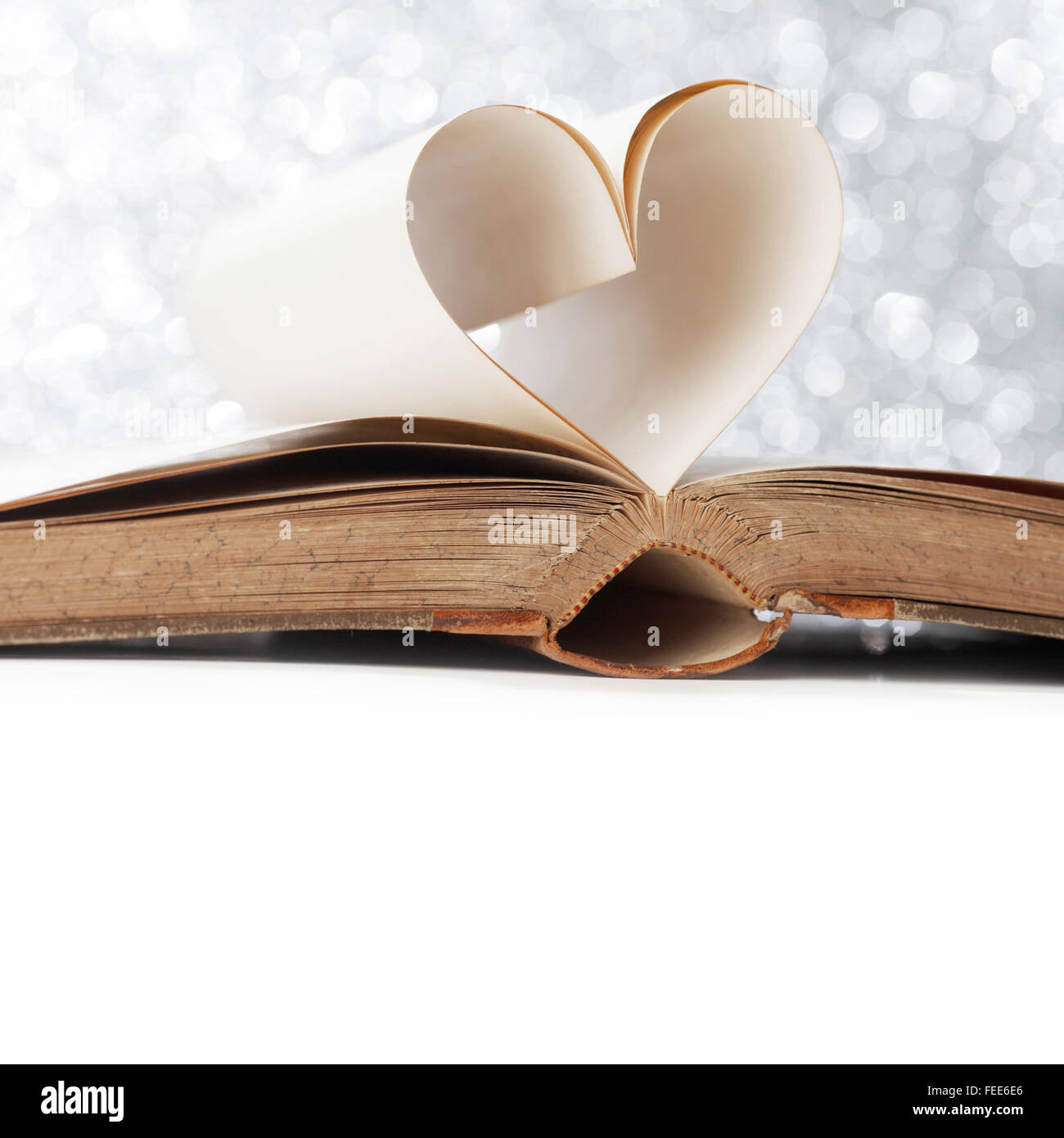 Pages of open book rolled in heart shape on glitter background Stock ...