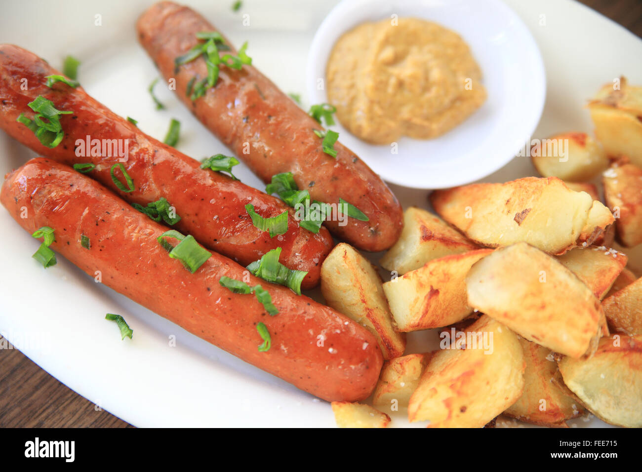 Sausages with home fries, mustard and chopped scallions Stock Photo - Alamy