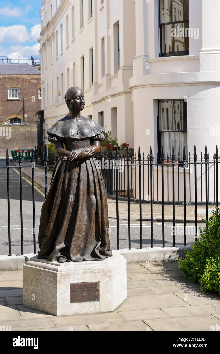 A bronze standing female sculpture in a small garden with an ...