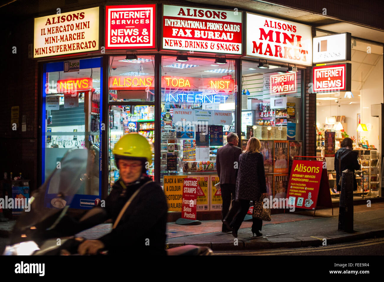 Night lights, sign, and passers-by of corner shop, Soho, London Stock ...