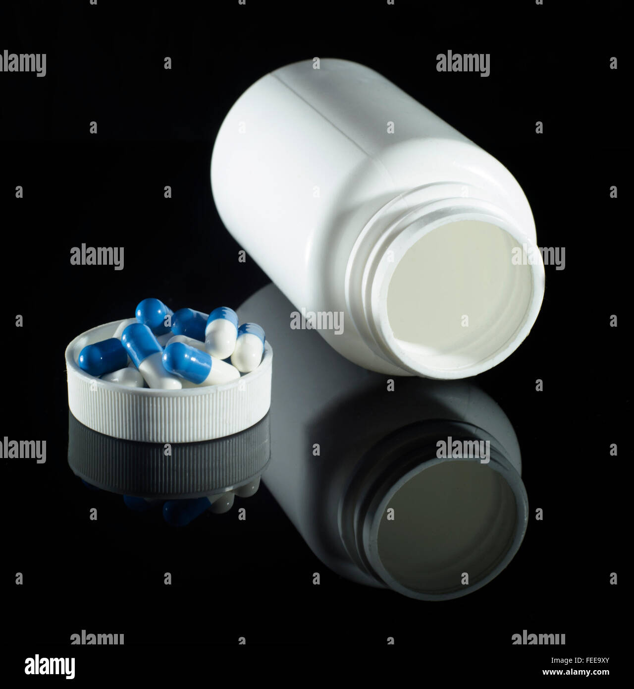 few pills with a white bottle with reflection Stock Photo - Alamy