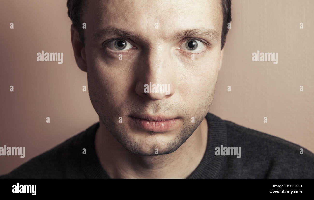 Young serious Caucasian man, close-up studio portrait over gray wall background, vintage ...