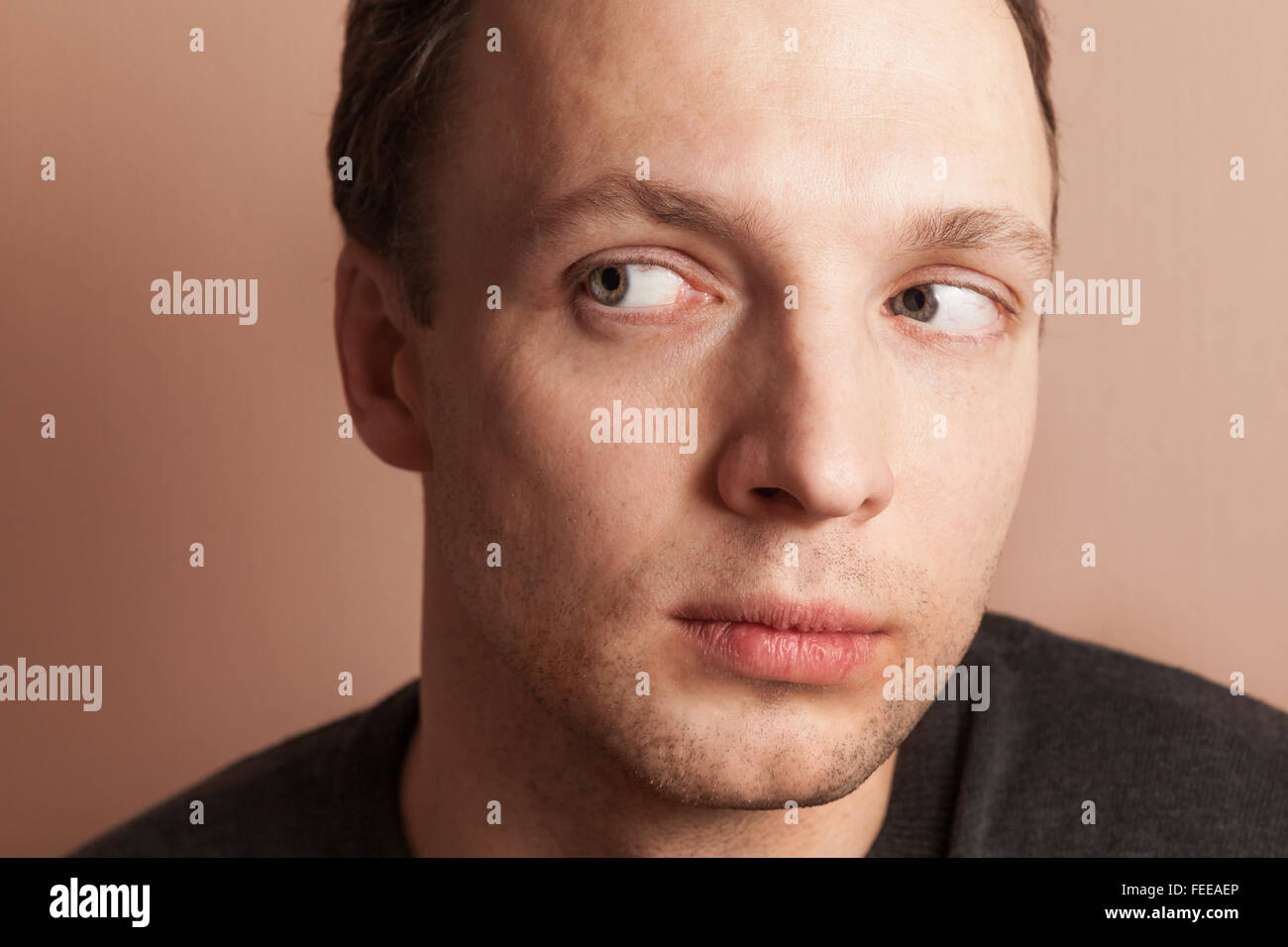 Young serious Caucasian man looking left, close-up studio portrait over ... Young serious Caucasian man looking left, close-up studio portrait over ...