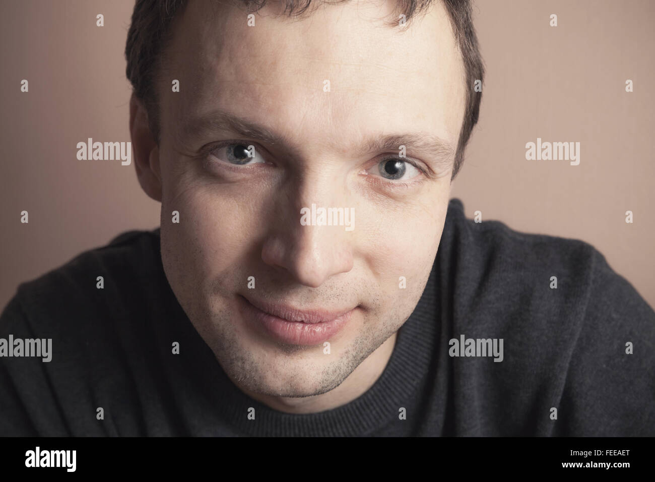 Young Caucasian man smiles, closeup studio portrait over gray wall ...