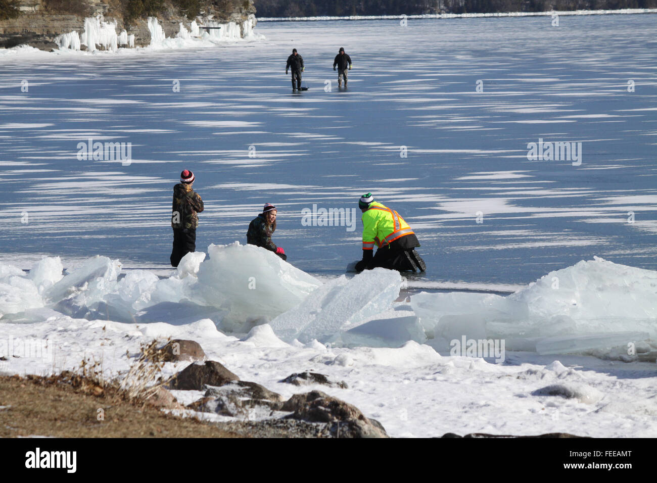 Two adult men with a plastic sled, walking across lake ice towards ...