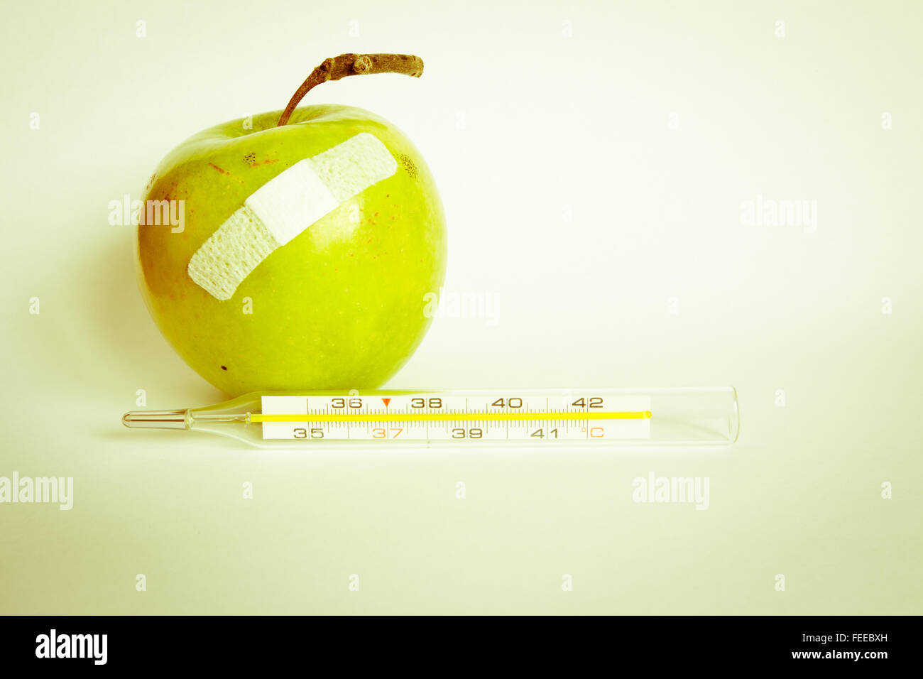 Damaged green apple and thermometer Stock Photo - Alamy