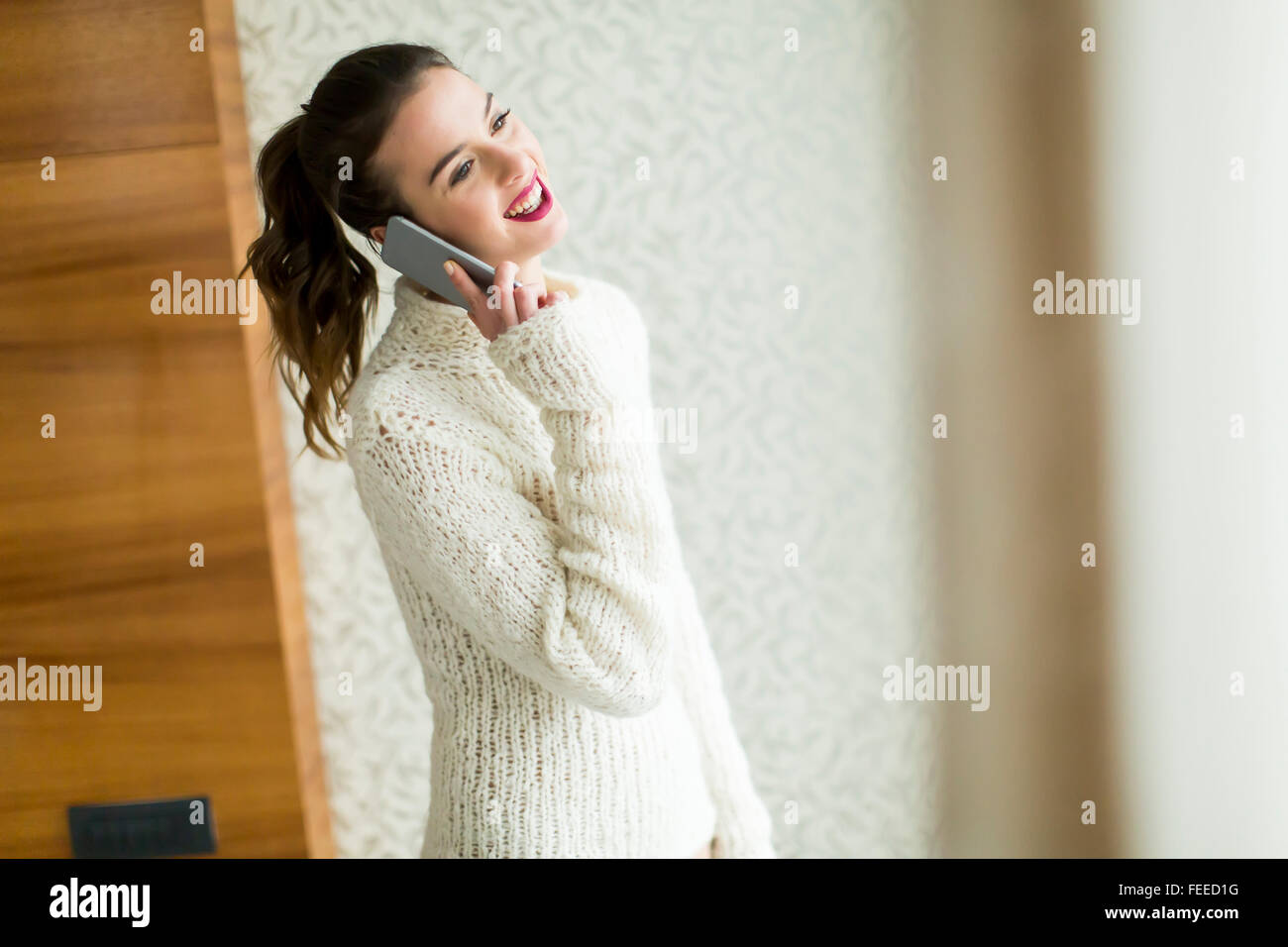 Young woman with telephone by window Stock Photo - Alamy