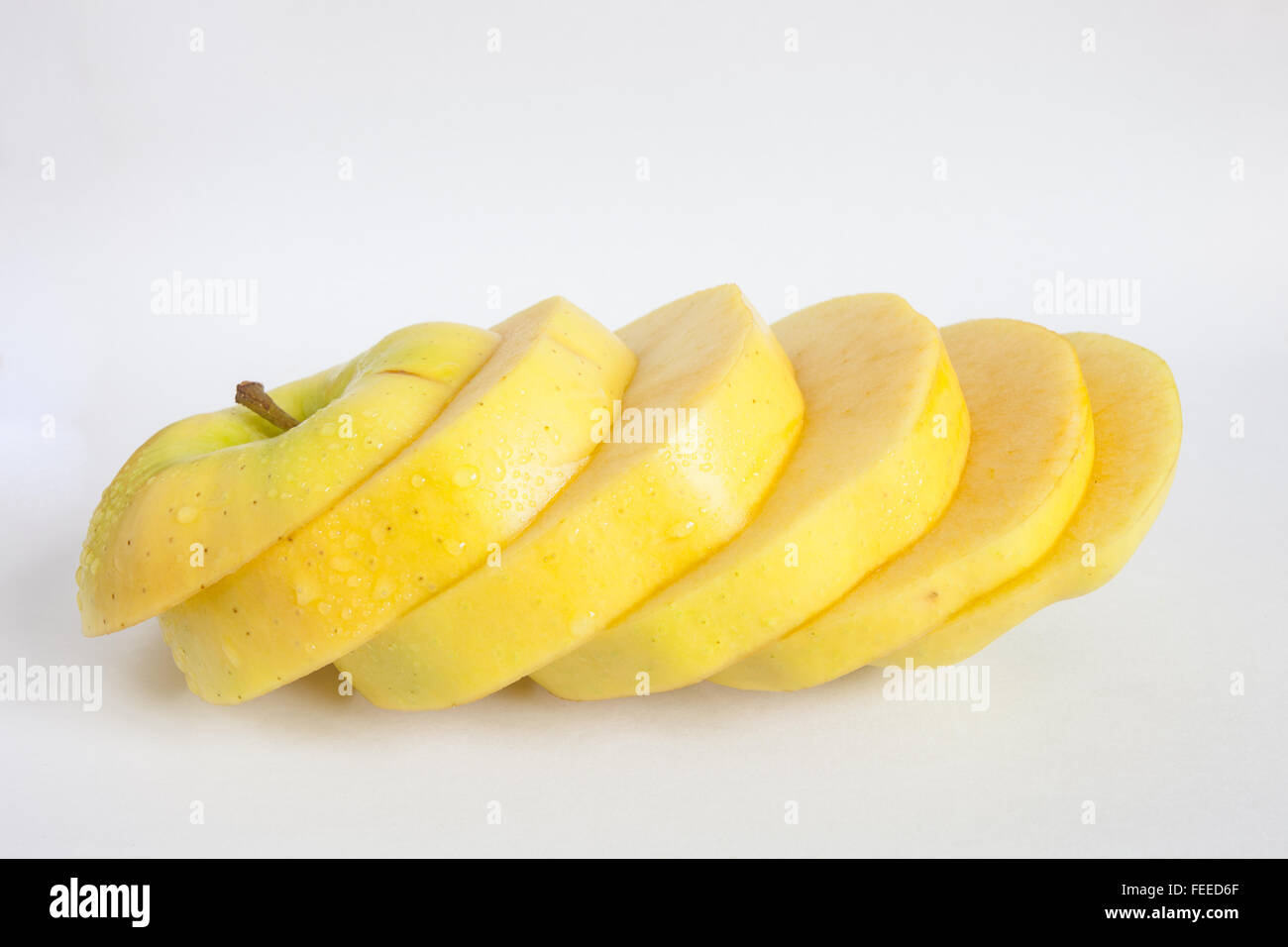 Single yellow apple cut into diagonal slices Stock Photo - Alamy