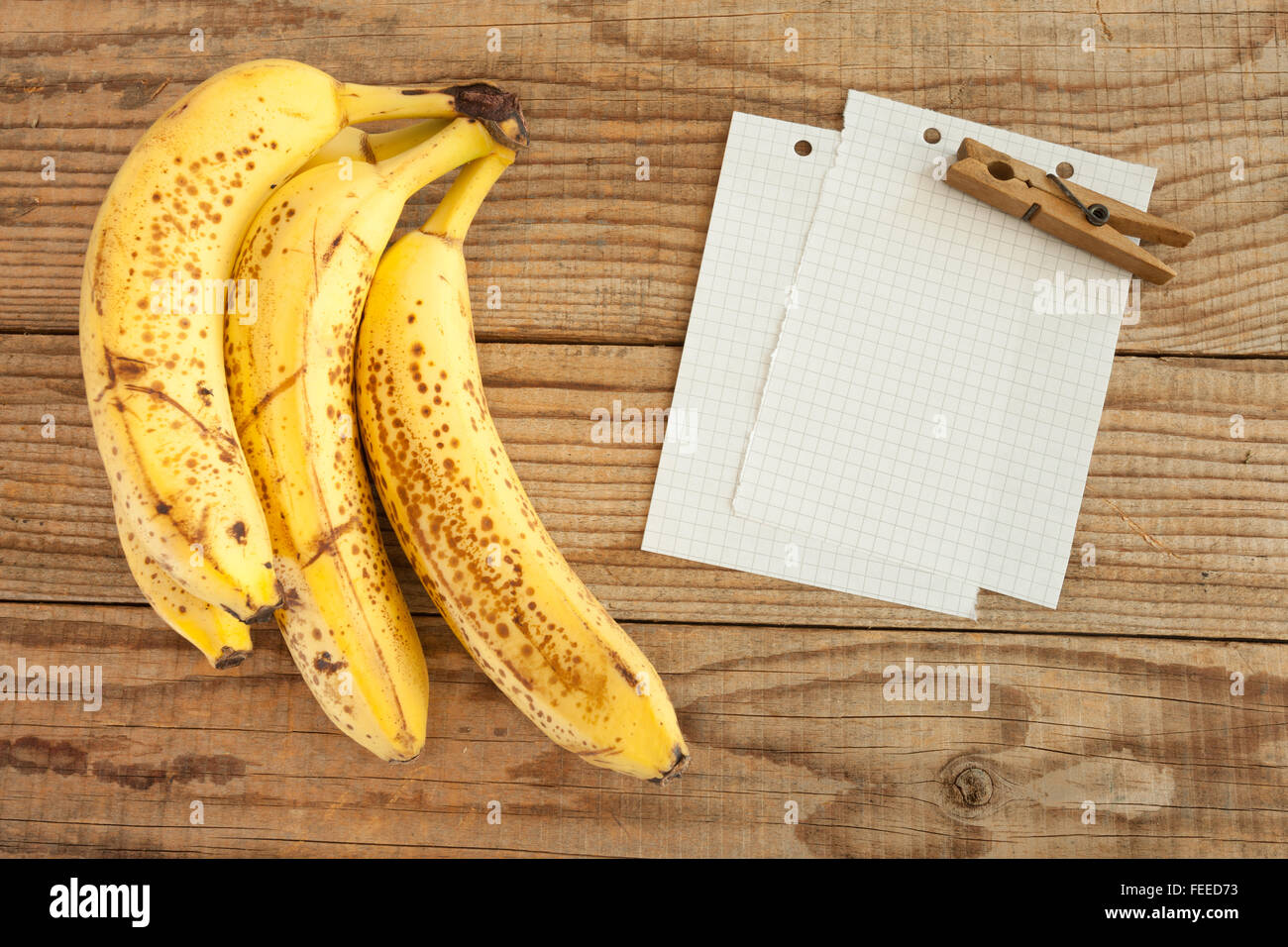 block note on wooden table next to four bananas Stock Photo - Alamy