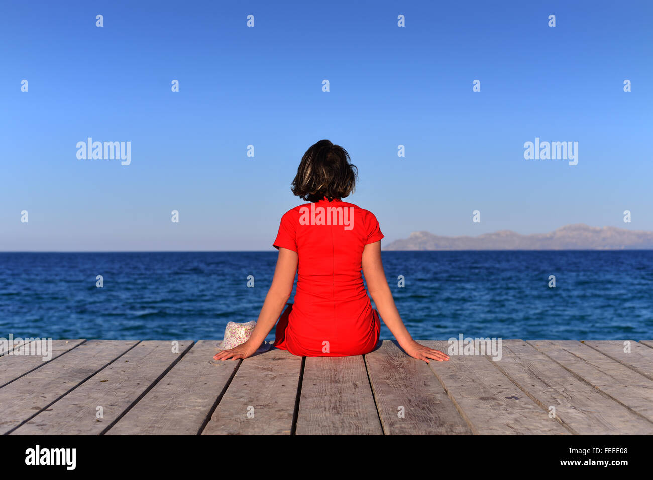 Beautiful single mature woman sat on edge of jetty at the Balearic ...