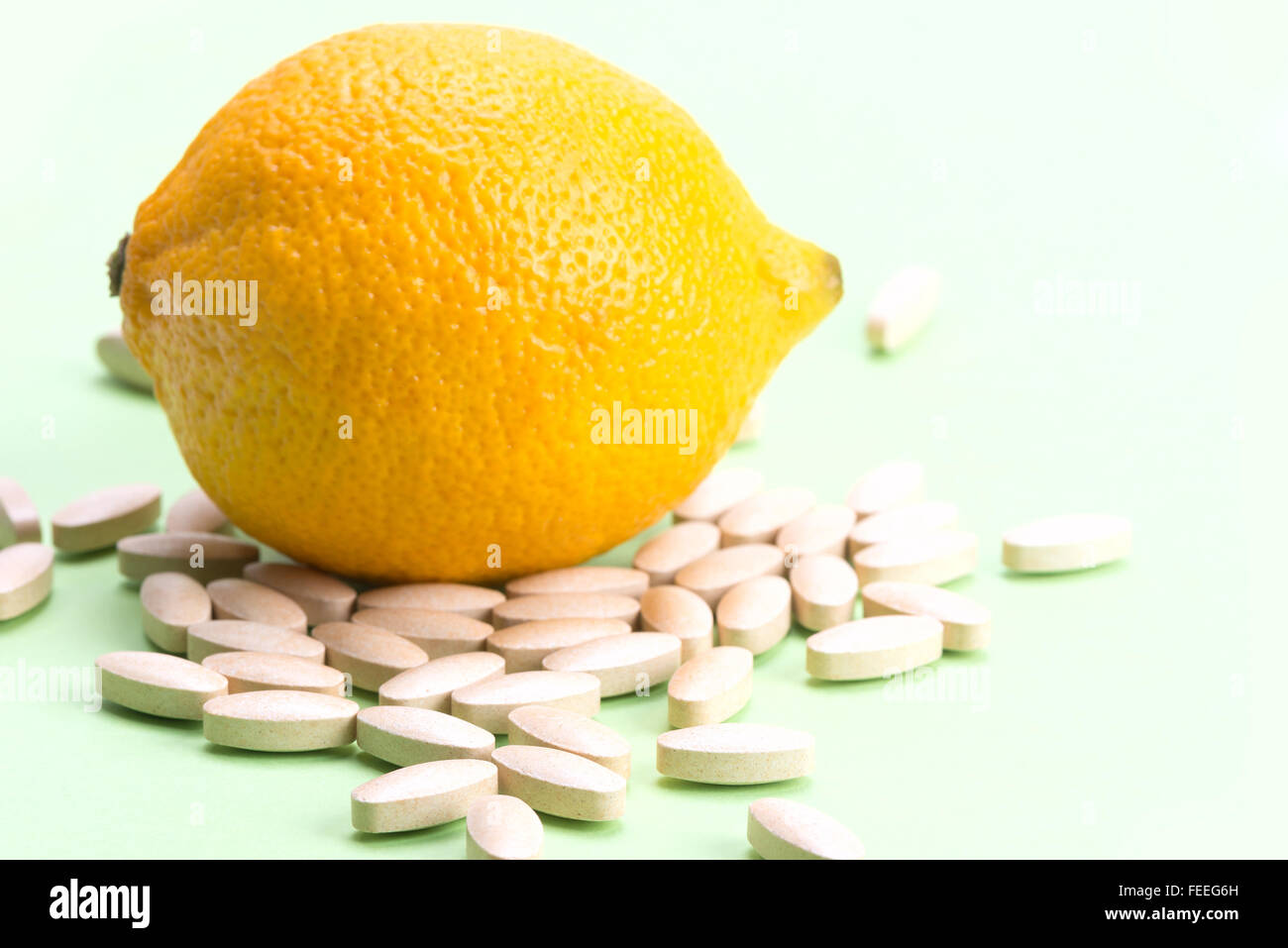 medical pills with vitamin C and lemon on a light green background ...
