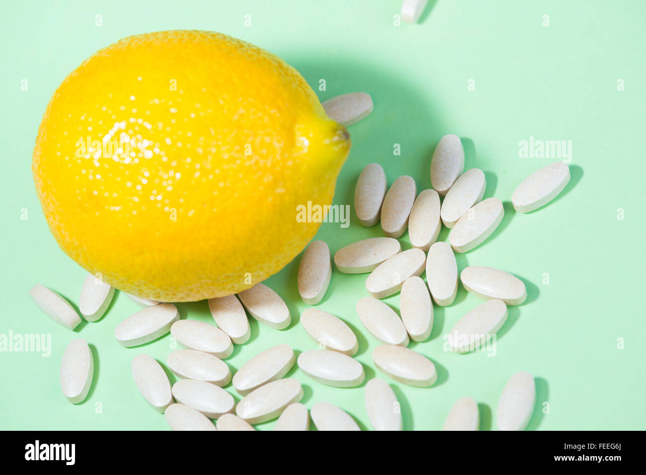 medical pills with vitamin C and lemon on a light green background ...