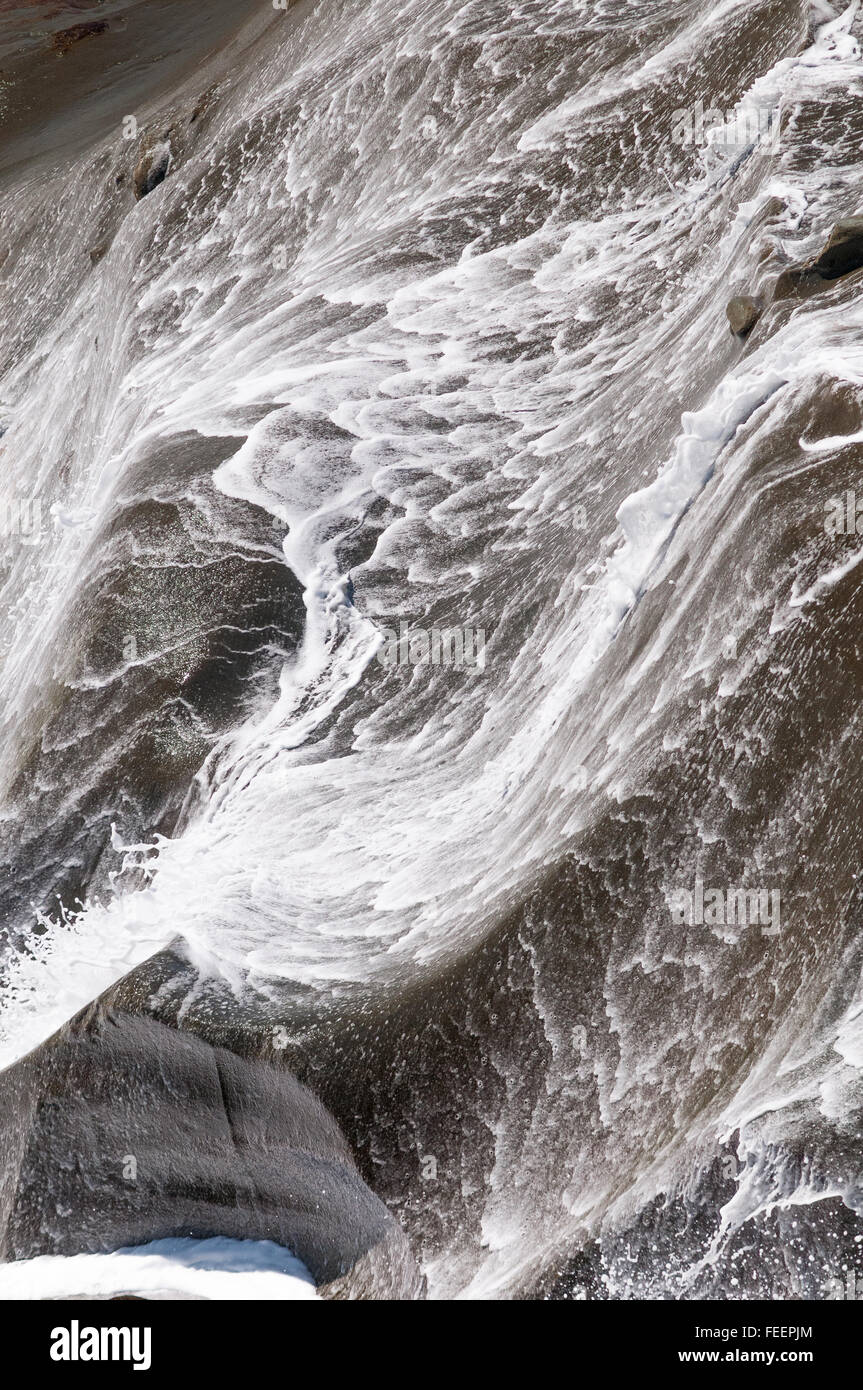 Water from crashing waves runs across weather smoothed sandstone Stock ...