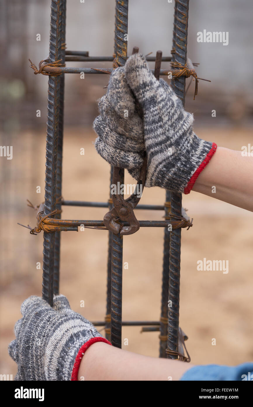 Close up of construction worker hands working with pincers on fixin ...