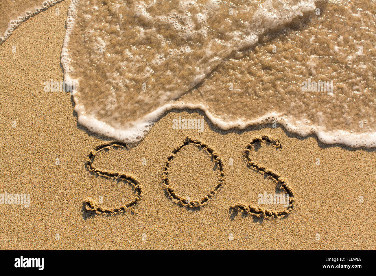 SOS - word drawn on the sand beach with the soft wave Stock Photo - Alamy