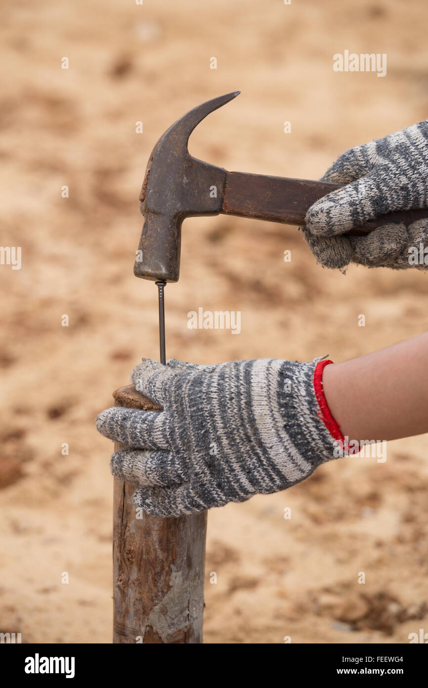 Worker hammering nail into wood at construction site Stock Photo - Alamy