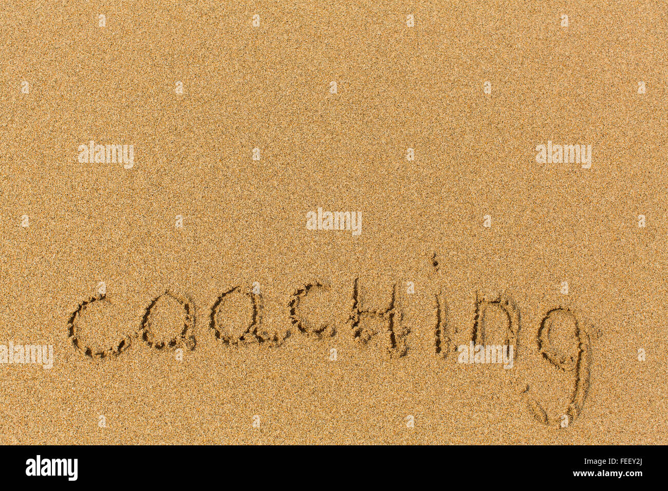 Coaching - word drawn on the sand beach. Background, texture of the ...