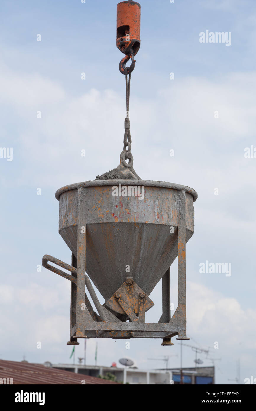 Crane lifting concrete mixer container against blue sky Stock Photo - Alamy