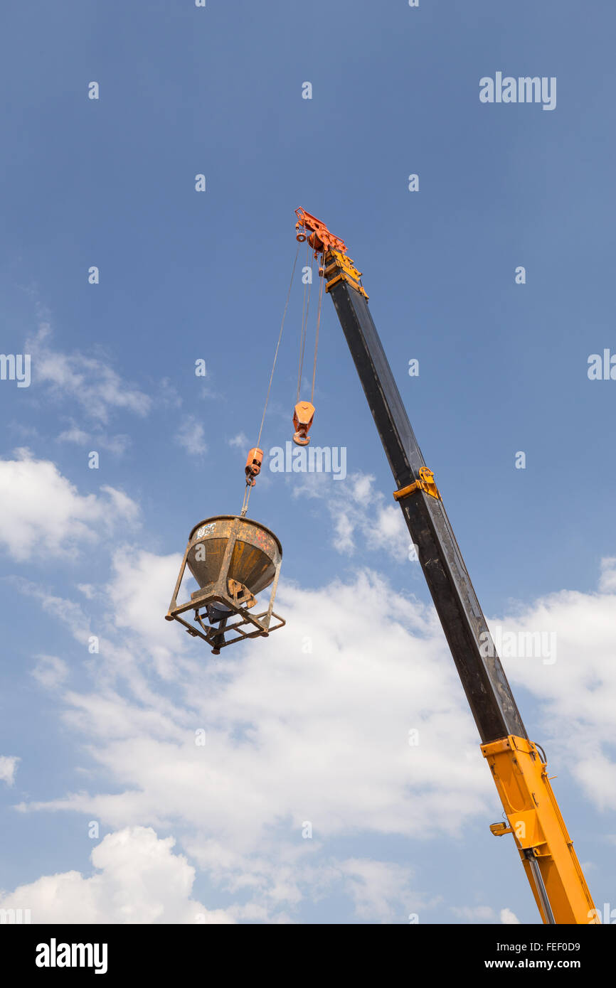 Crane lifting concrete mixer container against blue sky Stock Photo - Alamy