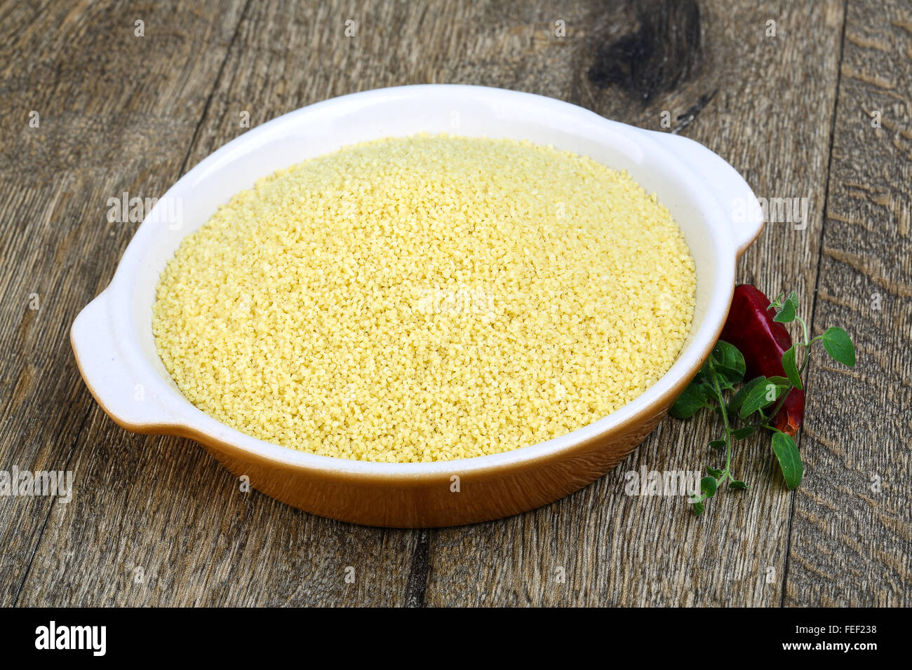Raw couscous with pepper and herbs on the wood background ready for ...