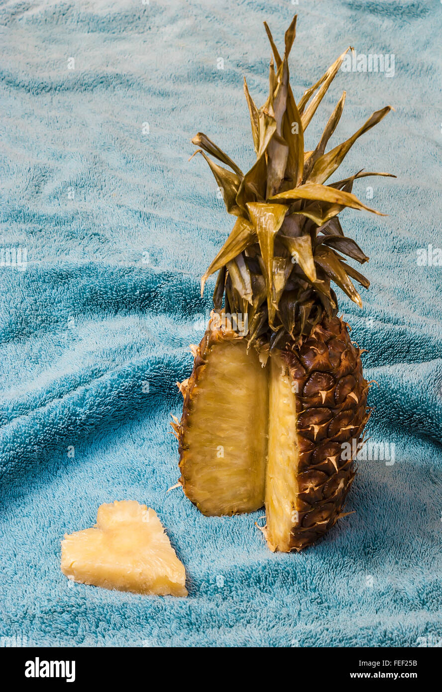 Pineapple and its heart shaped slice lying on blue background Stock ...