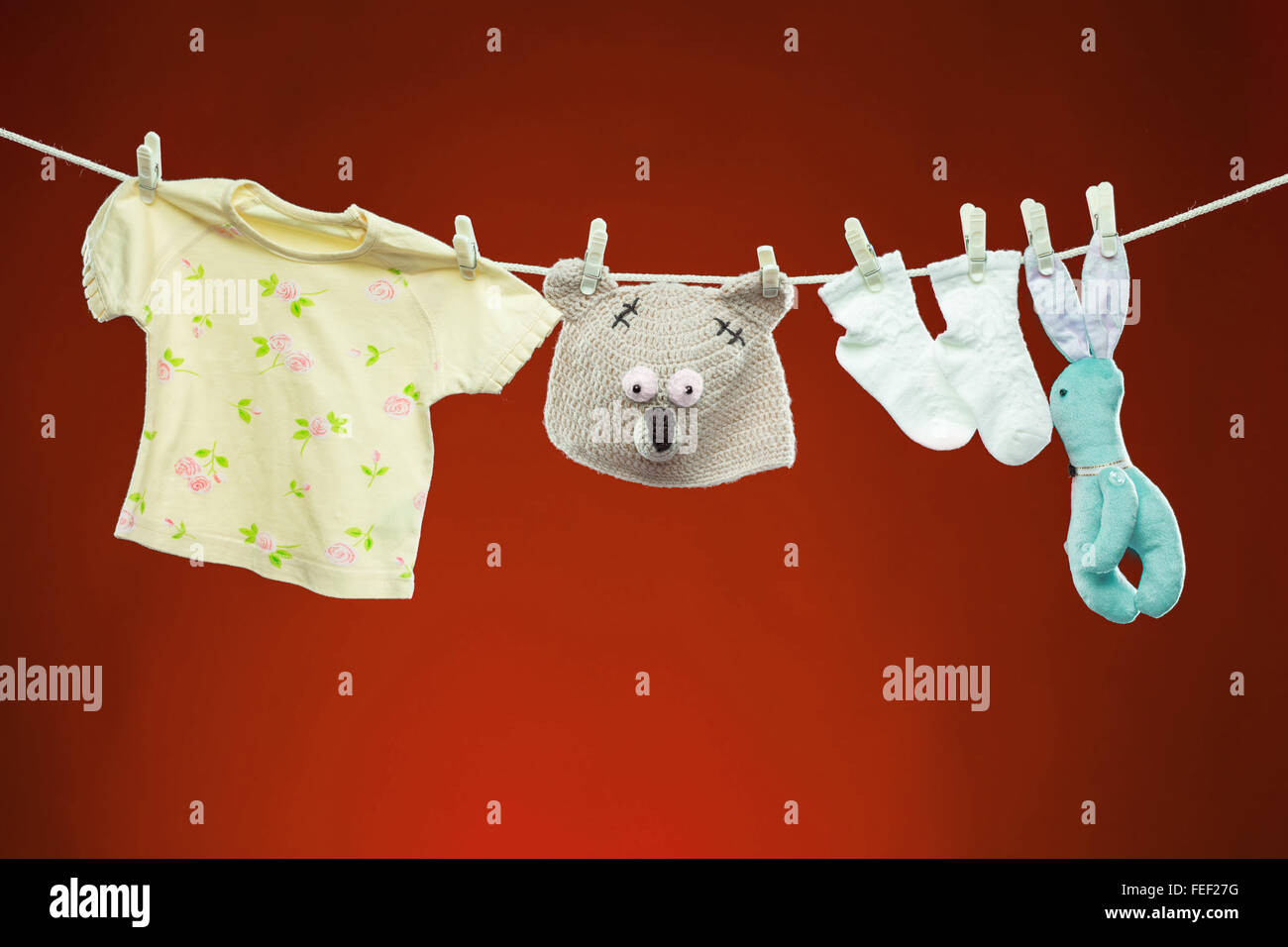 Baby goods hanging on the clothesline on red background Stock Photo - Alamy