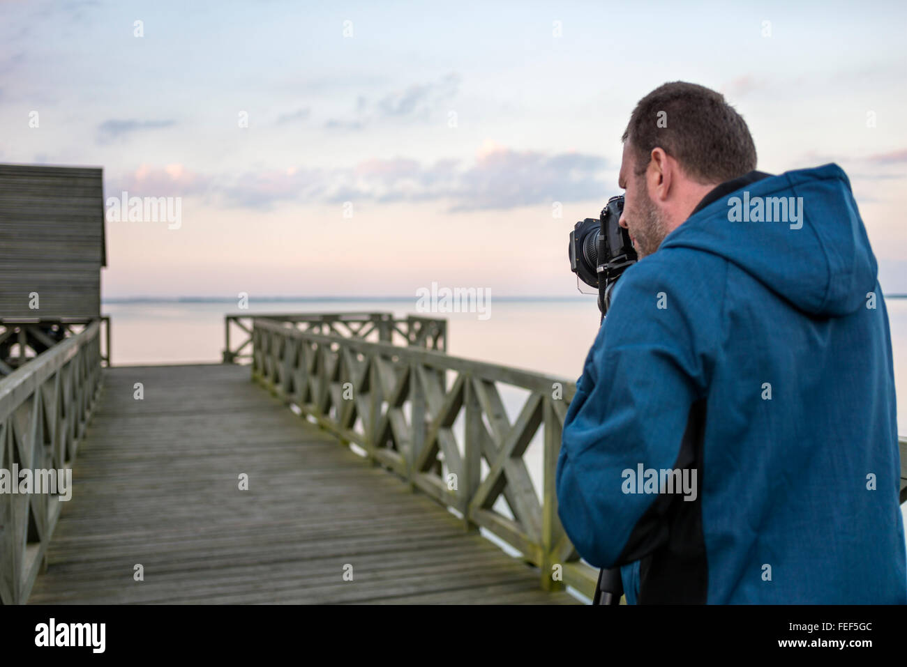 Professional photographer photographing landscape at the lake at sunset ...