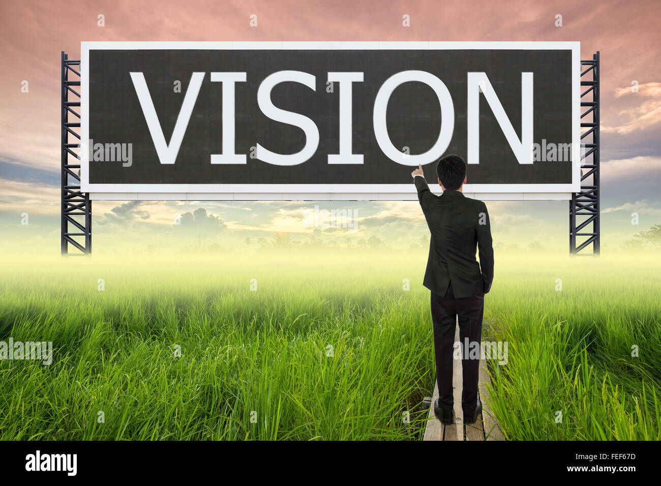 business man standing on wood bridge between rice field and pointing ...